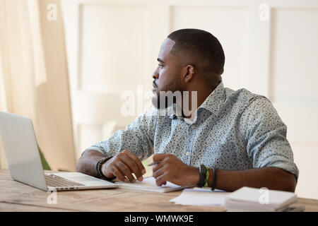 Young African man freelancer feeling tired of monotonous tasks, looking ...