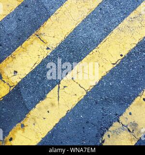 Yellow striped road markings on black asphalt highway. No parking is ...