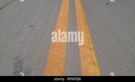 Yellow striped road markings on black asphalt highway. No parking is ...