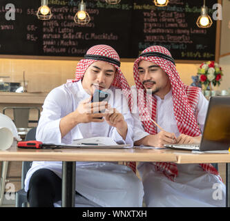 Arab man with beard holding laptop jumping against pink and purple ...