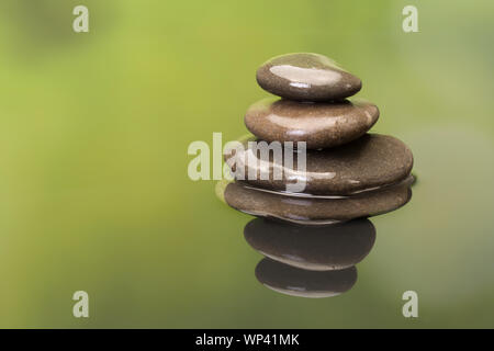 Stacked zen boulders reflected in green water Stock Photo - Alamy