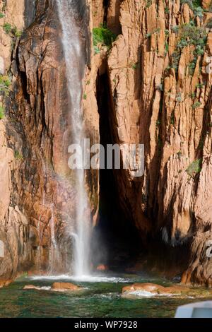 Background of a waterfall in front of a red cliff into the sea Stock ...