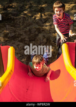 Two older brothers play and laugh with the youngest baby in a white bed ...