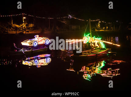 A flotilla of brightly illuminated boats are rowed down the River ...