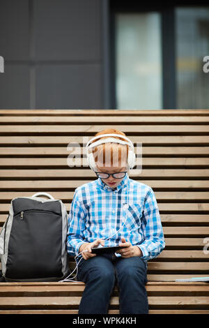 Cute boy using tablet with headphones lying on sofa at home Stock Photo ...