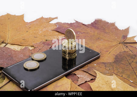 Smartphone on maple leaves background with some coins. Autumn ...