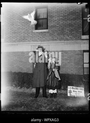 Man and child releasing birds near T.B. Christmas seals sign ca. 1935 ...