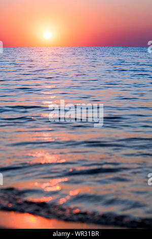 Sunset with large yellow sun under the sea surface. Calm ocean with ...