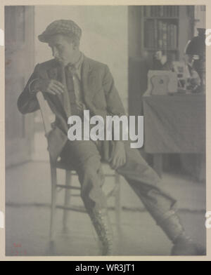 Maynard White in suit, wearing boots and cap, seated Stock Photo - Alamy