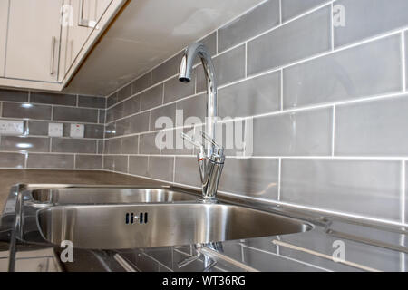 Typical kitchen sink taps with grey tiles Stock Photo - Alamy