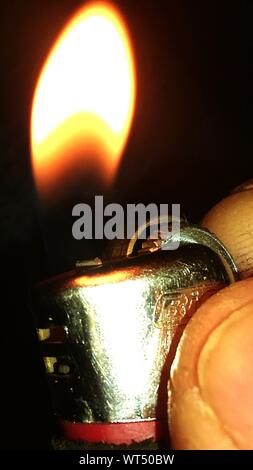 Hand holding lit cigarette lighter Stock Photo - Alamy