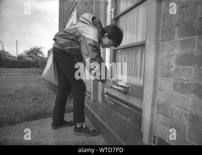 Paperboy delivering newspapers on his paper round in Hampshire in the ...