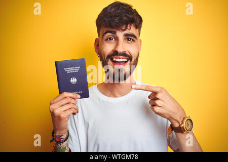 Young man with tattoo wearing German Germany passport over isolated ...