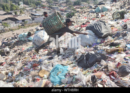 A scavenger sorts and collects plastics for recycling at the garbage ...