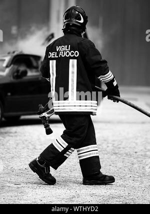 A firefighter in a dark uniform and helmet is the central figure, with ...