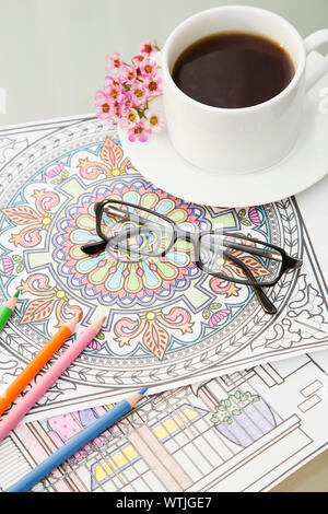 Coloring page, eyeglasses, pencils and cup of coffee on dark wooden ...