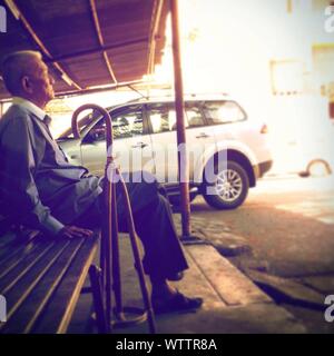 man waiting at bus stop on street for late night bus anniesland cross ...