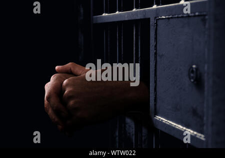 A closeup of a dimly lit prison holding cell door with a pair of ...