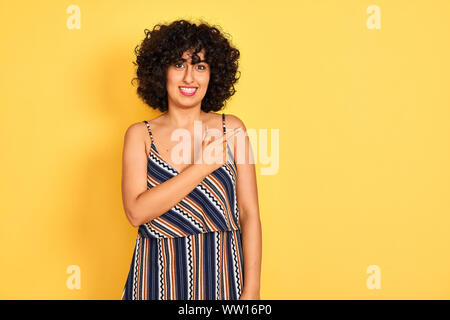 Young arab woman with curly hair wearing striped dress over isolated ...