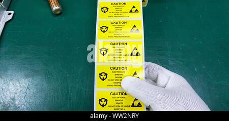 Hand holding ESD symbol label with antistatic gloves on gray background ...