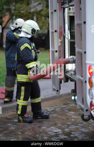 A member of the fire brigade holds a water supply hose from the fire ...