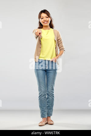 Young asian woman pointing finger at her cheek while taking selfie ...