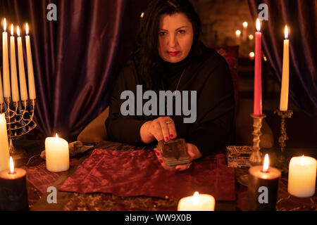 Woman fortune-teller guesses fate of night at table with candles Stock ...