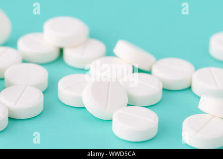 Heap of white pills on colored background. Tablets scattered on a table ...
