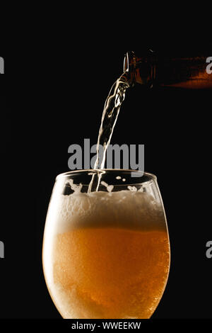 beer flowing from bottle into glass isolated on black Stock Photo - Alamy