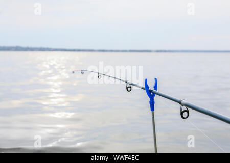 Modern fishing rod on holder near river Stock Photo - Alamy