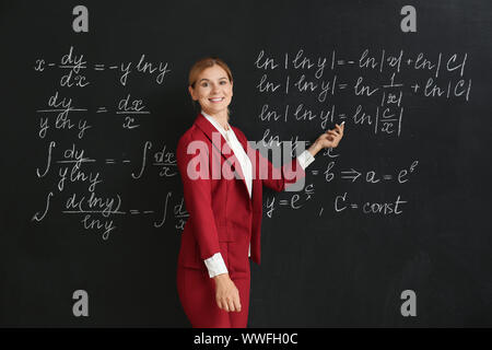 Beautiful math teacher near blackboard in classroom Stock Photo - Alamy