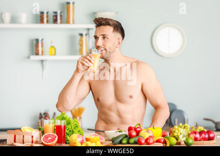 Handsome muscular man drinking juice in kitchen. Weight loss concept ...