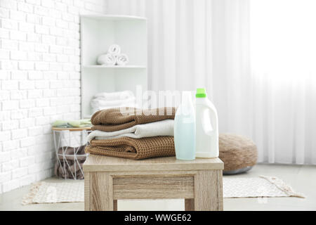 Stack of clean clothes and washing agents on table in bathroom Stock ...