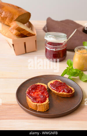 Toasts with peanut butter and berry jam on a plate on a wooden table ...