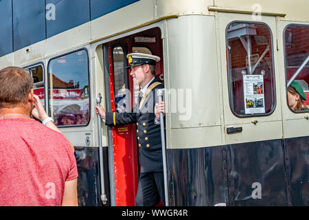 Man dressed as bus conductor on open platform of traditional style ...