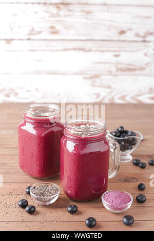 Glass jars with acai smoothie and berries on blurred background Stock ...