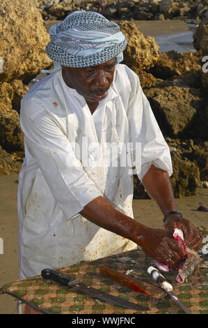 Dark skinned fishmonger cuts up fresh fish Stock Photo - Alamy