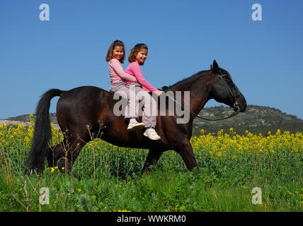twins sisters horseback riding a black stallion Stock Photo - Alamy