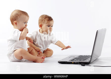 Two cute babies playing with laptop Stock Photo - Alamy