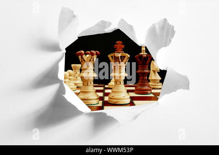 chess pieces behind hole in blank paper Stock Photo - Alamy