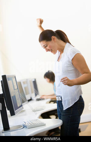 Woman standing in computer room cheering and smiling Stock Photo - Alamy