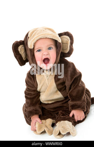 Vertical shot of an adorable monkey sitting on a stone with closed eyes ...