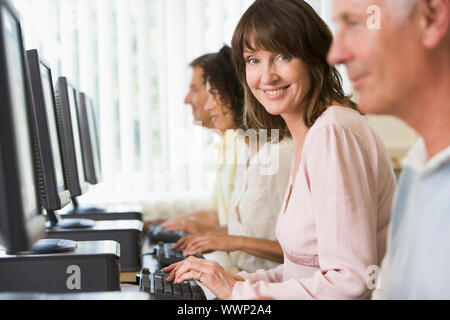 Four people sitting at computer terminals (depth of field/high key ...