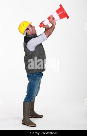 Construction worker shouting into a traffic cone Stock Photo - Alamy