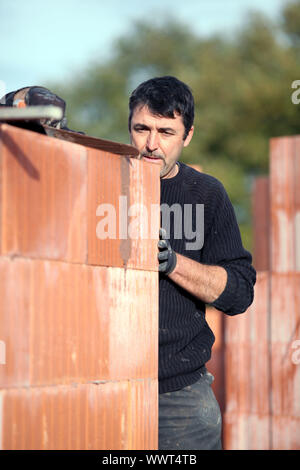 Hard working bricklayer laying concrete blocks on top of concrete ...