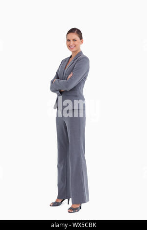Smiling tradeswoman with her arms folded against a white background ...