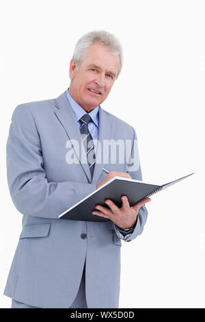 Smiling mature tradesman with his notebook against a white background ...