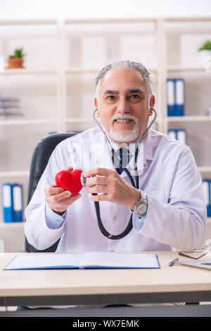 Aged male doctor cardiologist with heart model Stock Photo - Alamy