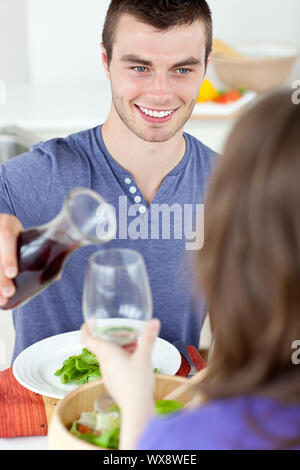 Handsome adult man tasting vegetables dish near laptop in home interior ...