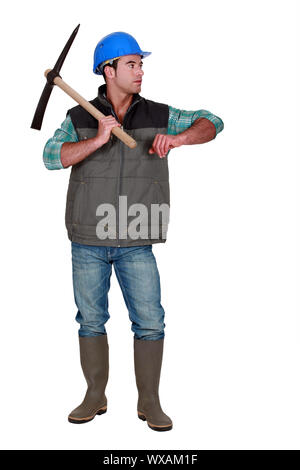 Construction worker leaning on a pickaxe Stock Photo - Alamy